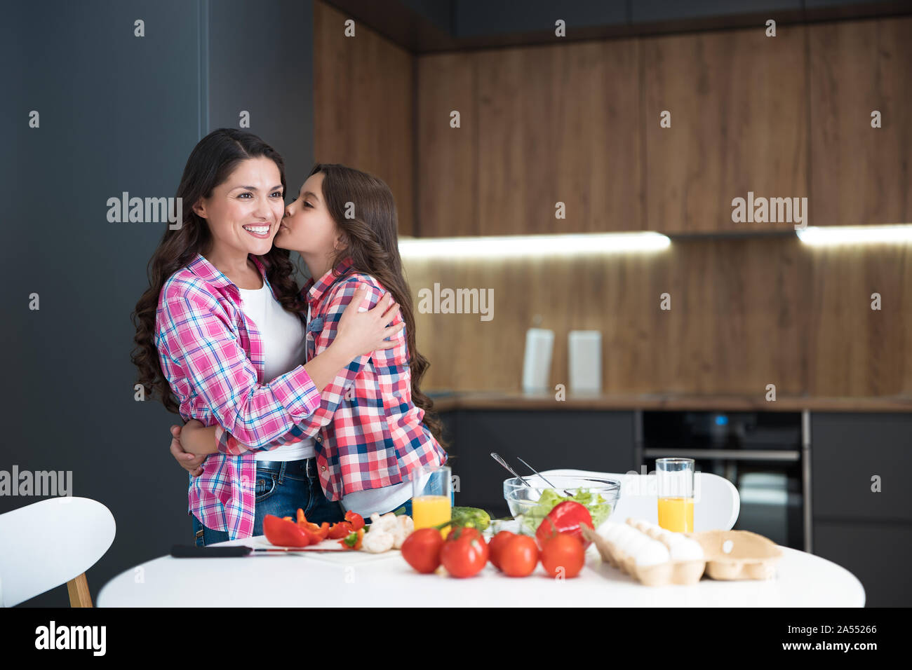 young beautiful woman and her cute teen daughter cooking breakfast in ...