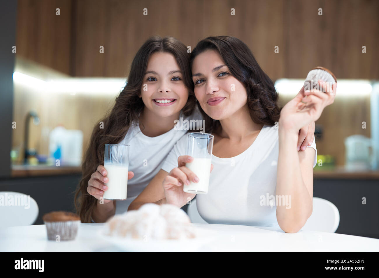 beautiful young brunette mother with her cute teenager daughter eating ...