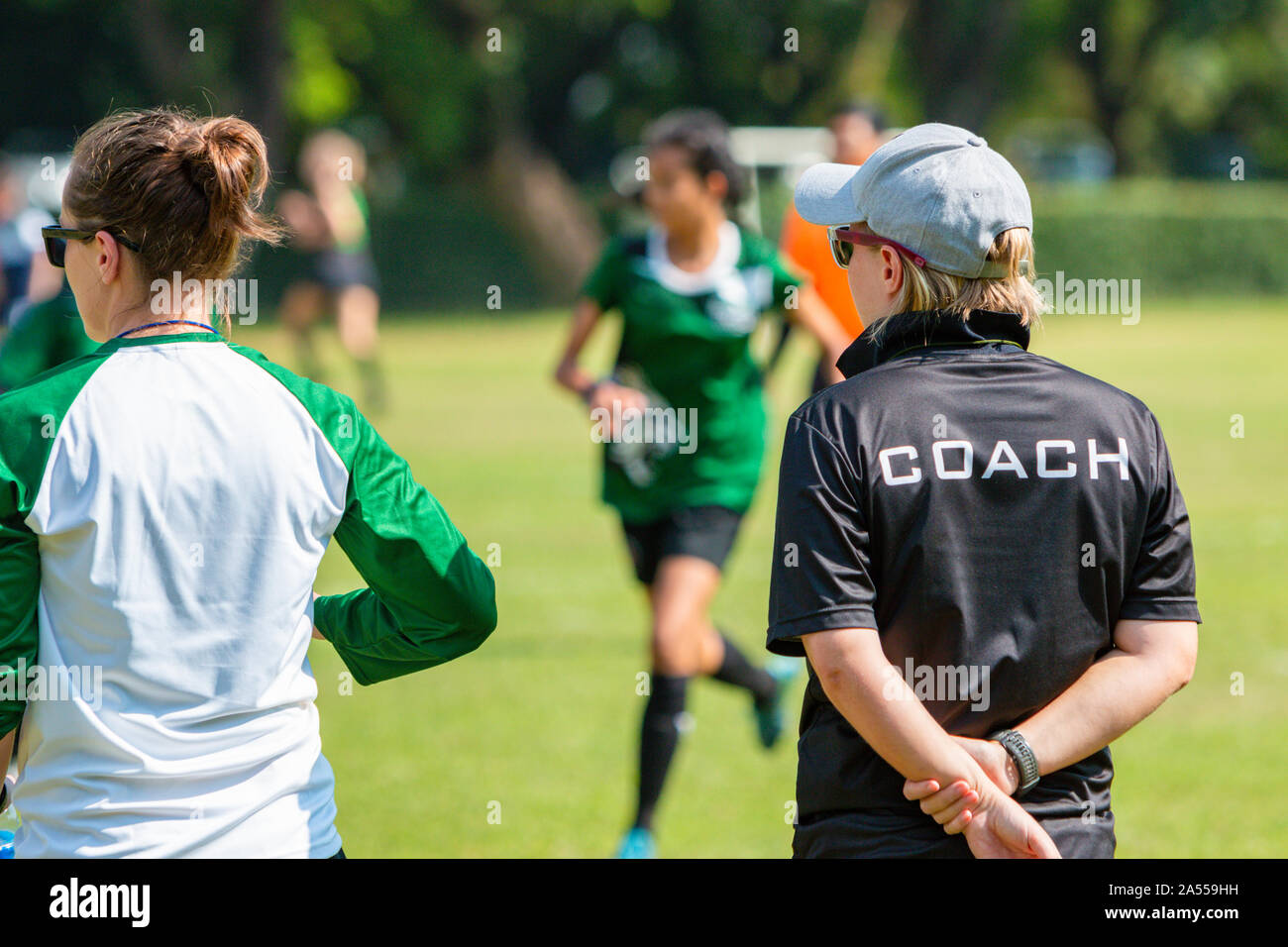 Back view of a female soccer, football, coach in black coach shirt ...