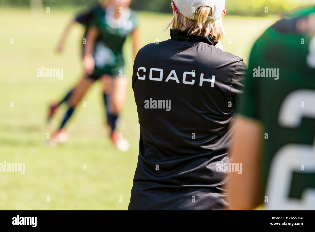 Back view of a female soccer, football, coach in black coach shirt ...