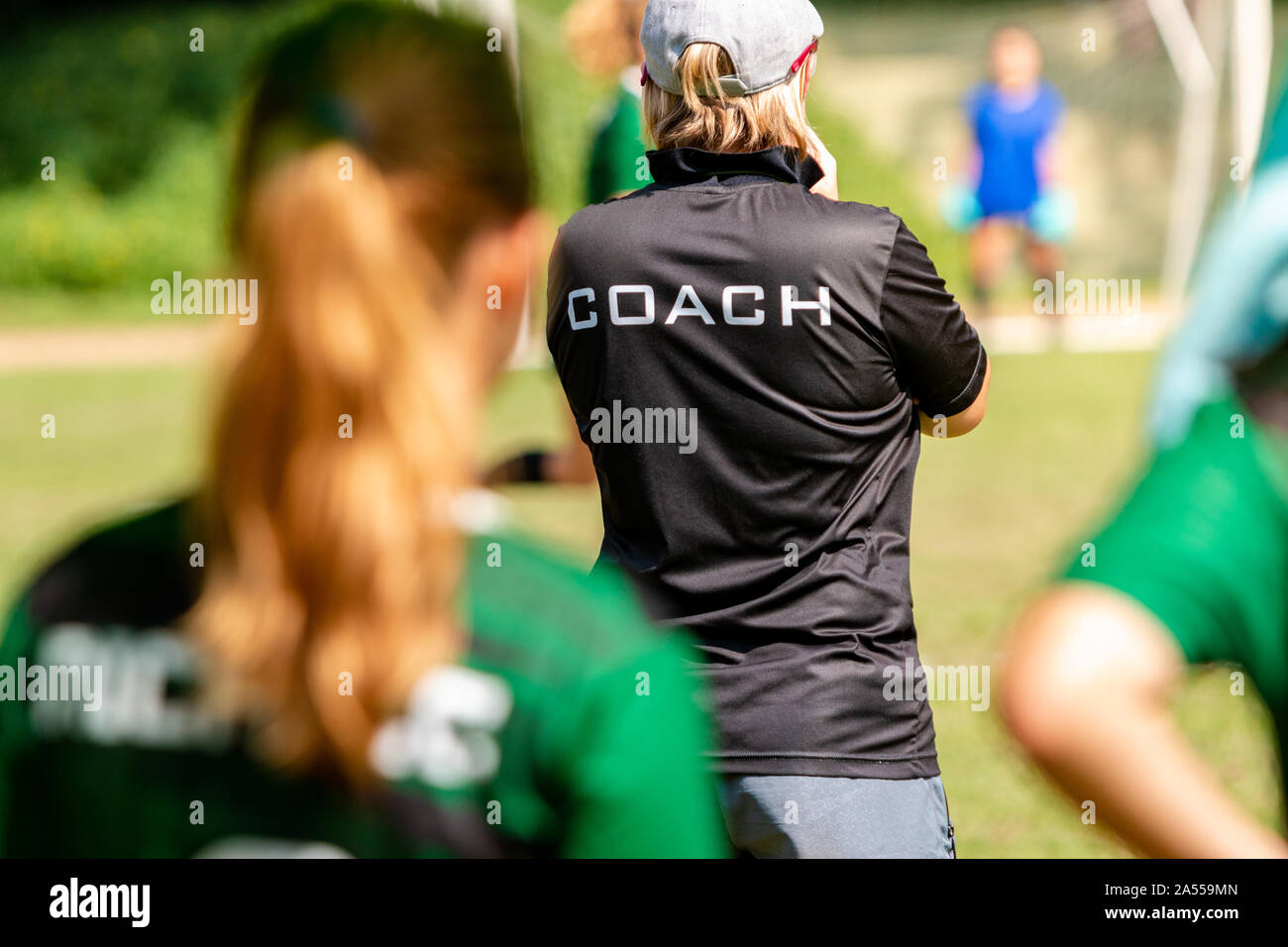 Back view of a female soccer, football, coach in black coach shirt ...