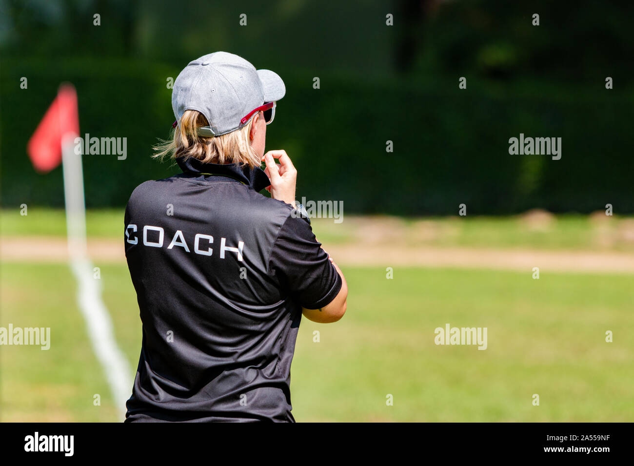 Back view of a female soccer, football, coach in black coach shirt ...