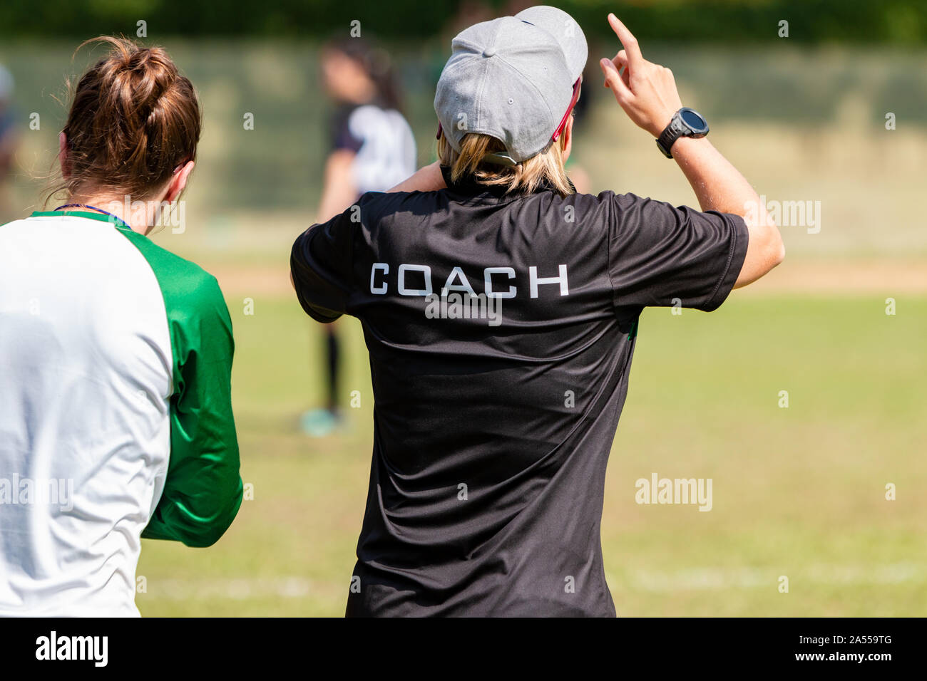 Back view of a female soccer, football, coach in black coach shirt ...