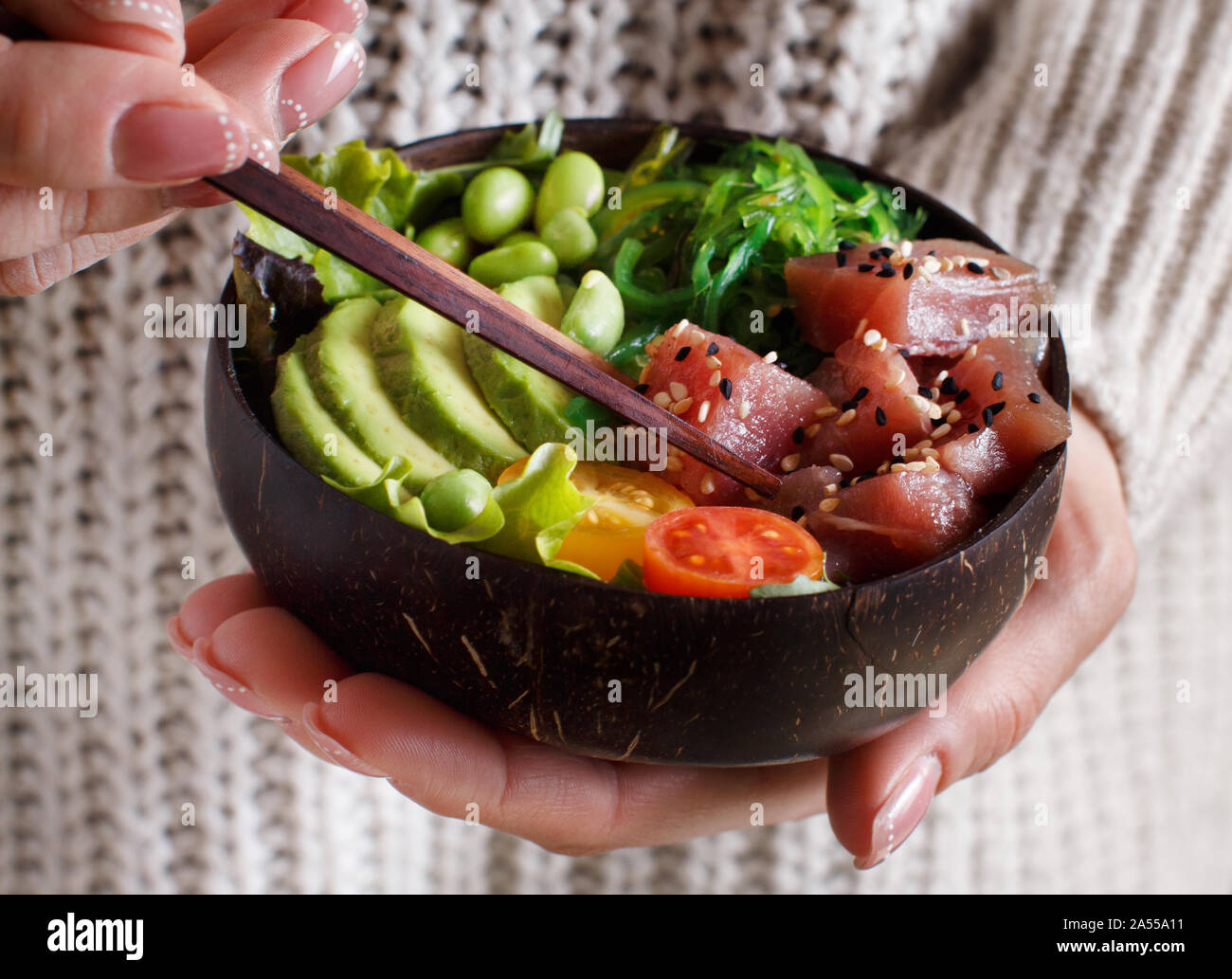 Girl eating hawaiian tuna poke salad in the bowl Stock Photo - Alamy