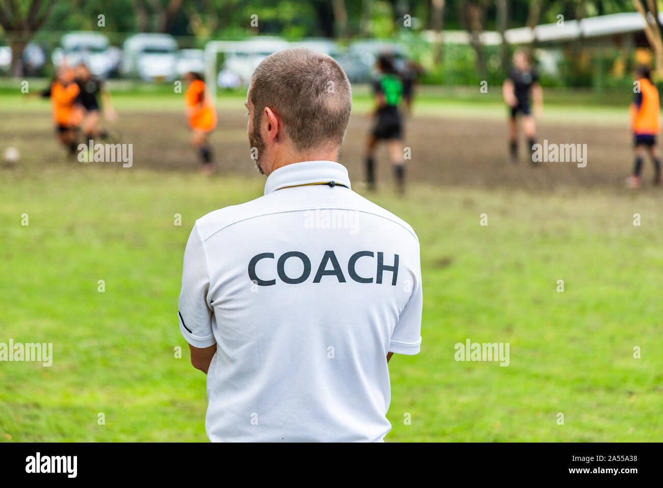 Back view of a male soccer, football, coach in white coach shirt ...