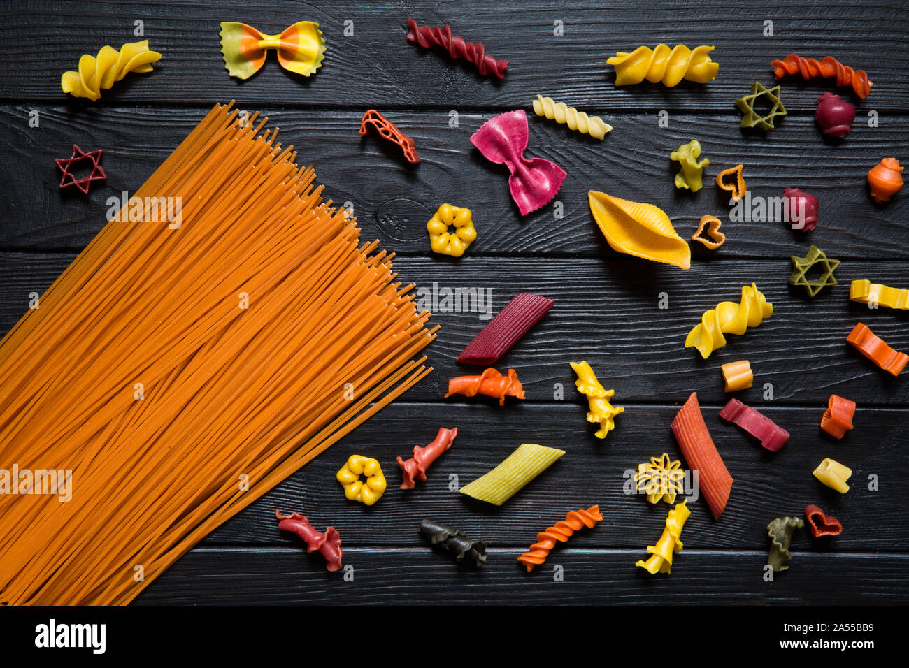 Different kinds of pasta on black background. Yellow conchiglie, color ...