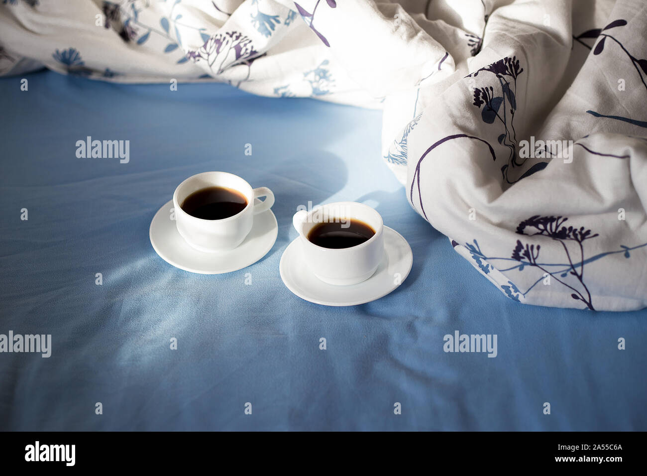 Two white cups of coffee are in bed, sunny morning Stock Photo - Alamy
