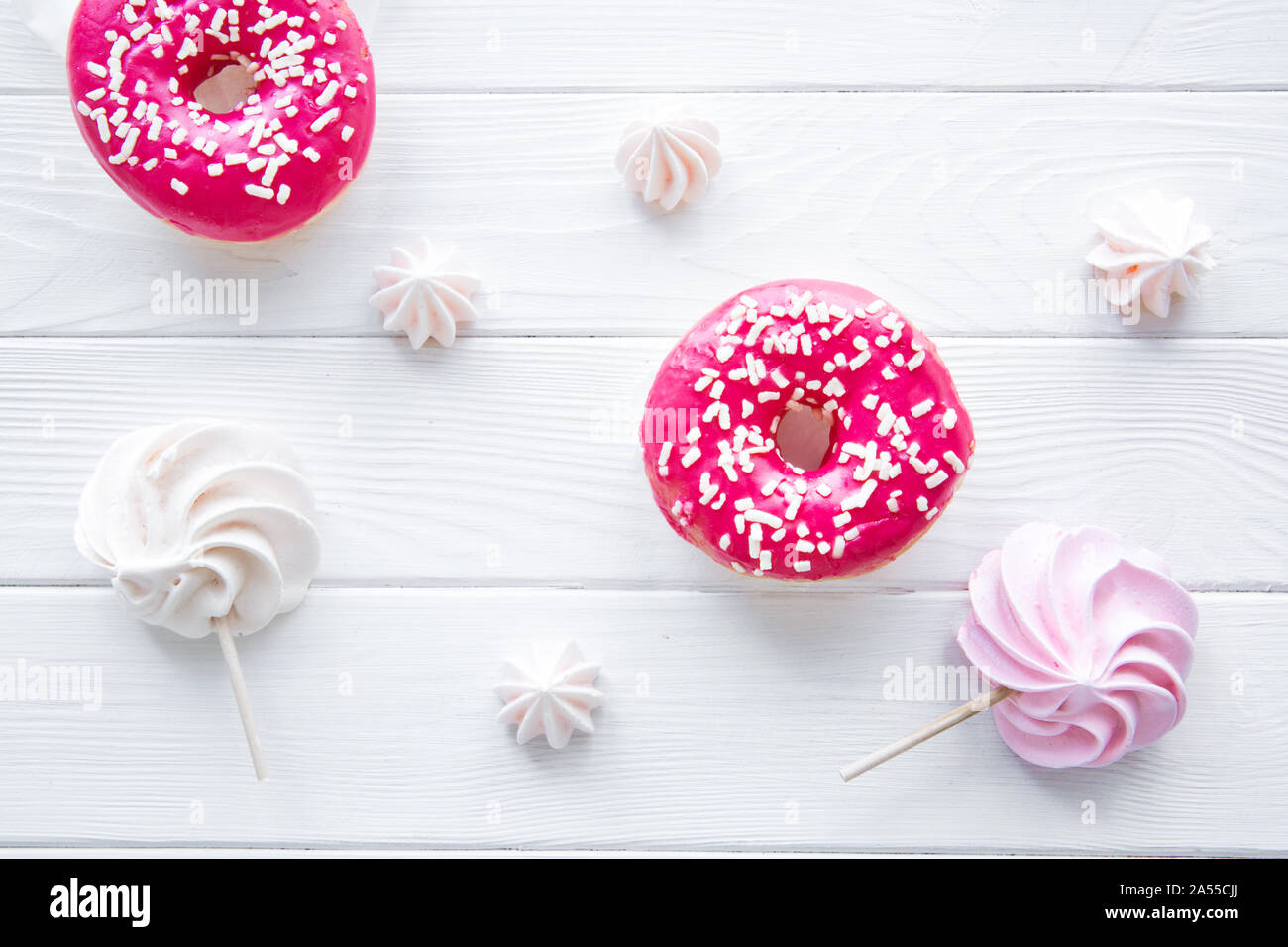Pink doughnuts with sprinkles and white meringue sweets background ...