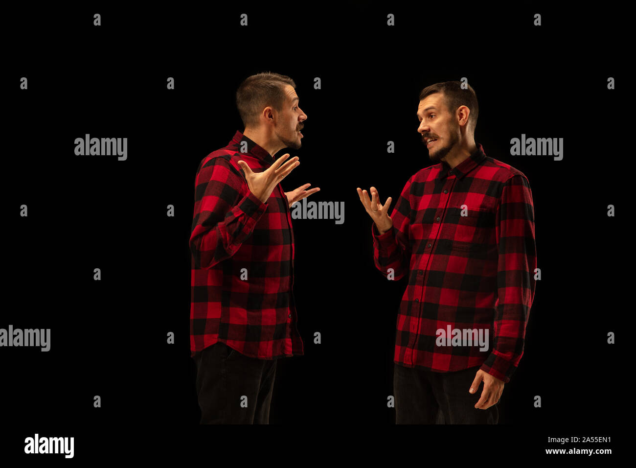 Young handsome man arguing with himself on black studio background ...