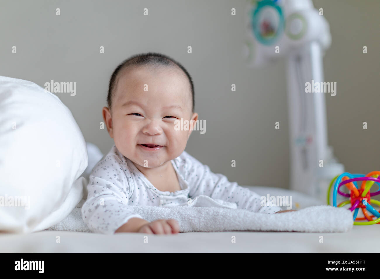 Adorable baby smiling boy doing tummy time on bed. Family morning at ...
