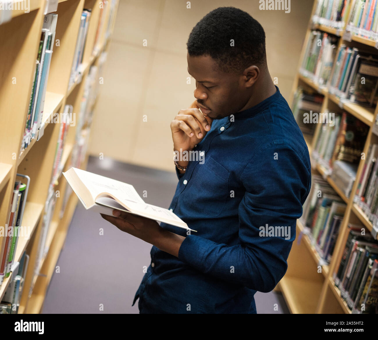 Young black man choosing book in public library Stock Photo - Alamy