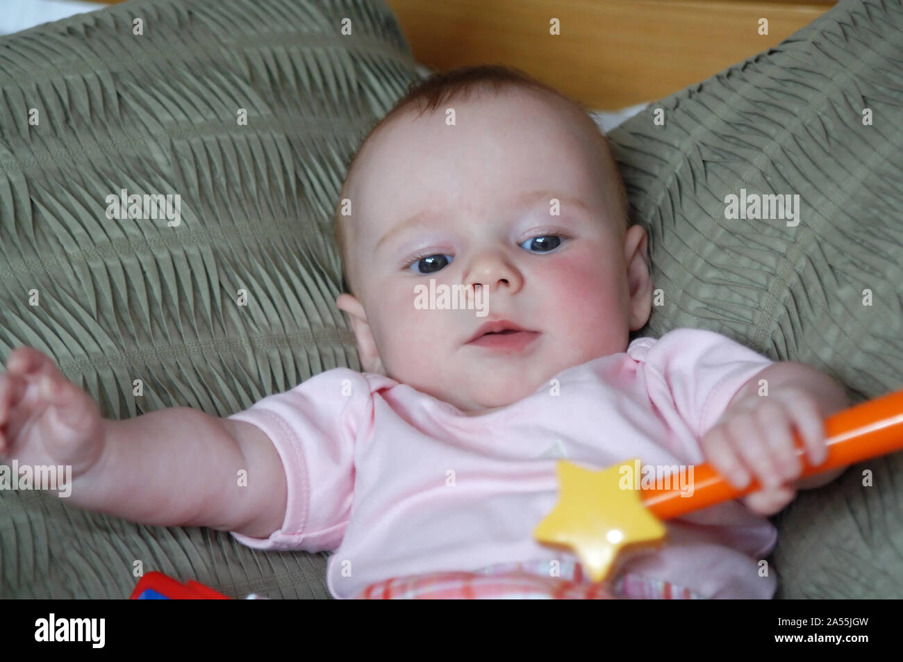 baby girl gripping a toy Stock Photo - Alamy