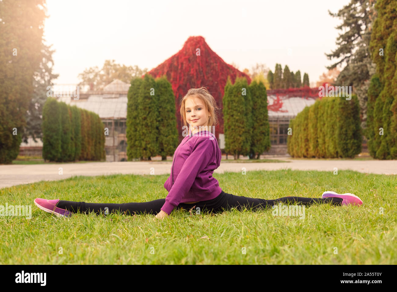Outdoors leisure. Little gymnast doing splits in the autumn park ...