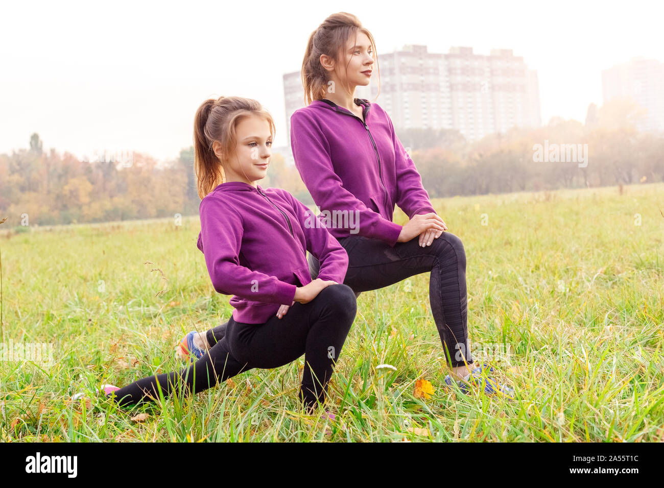 Outdoors leisure. Sisters doing lunge exercise in the autumn park ...