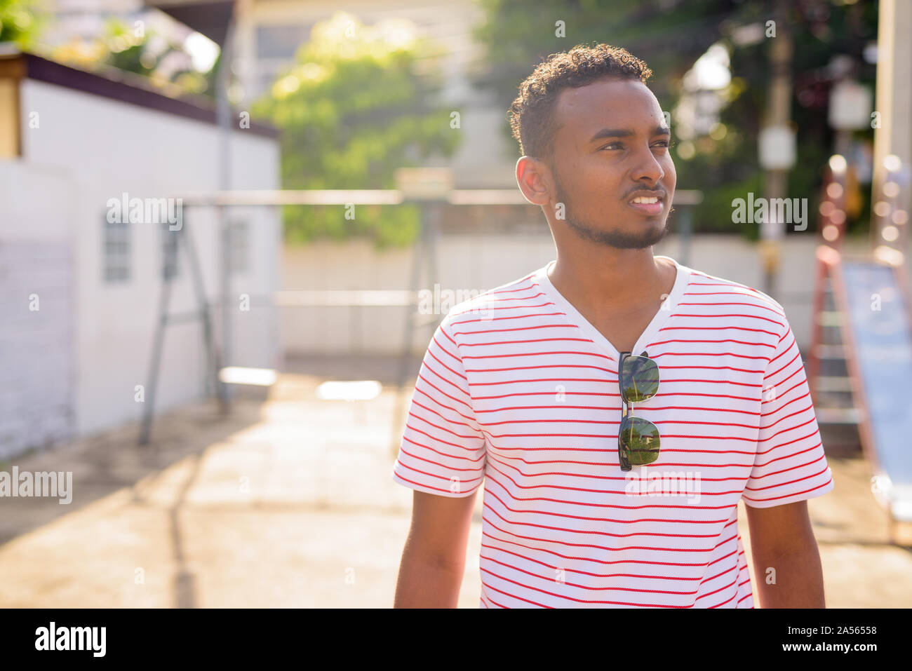 Happy young African bearded man with Afro hair thinking outdoors Stock ...