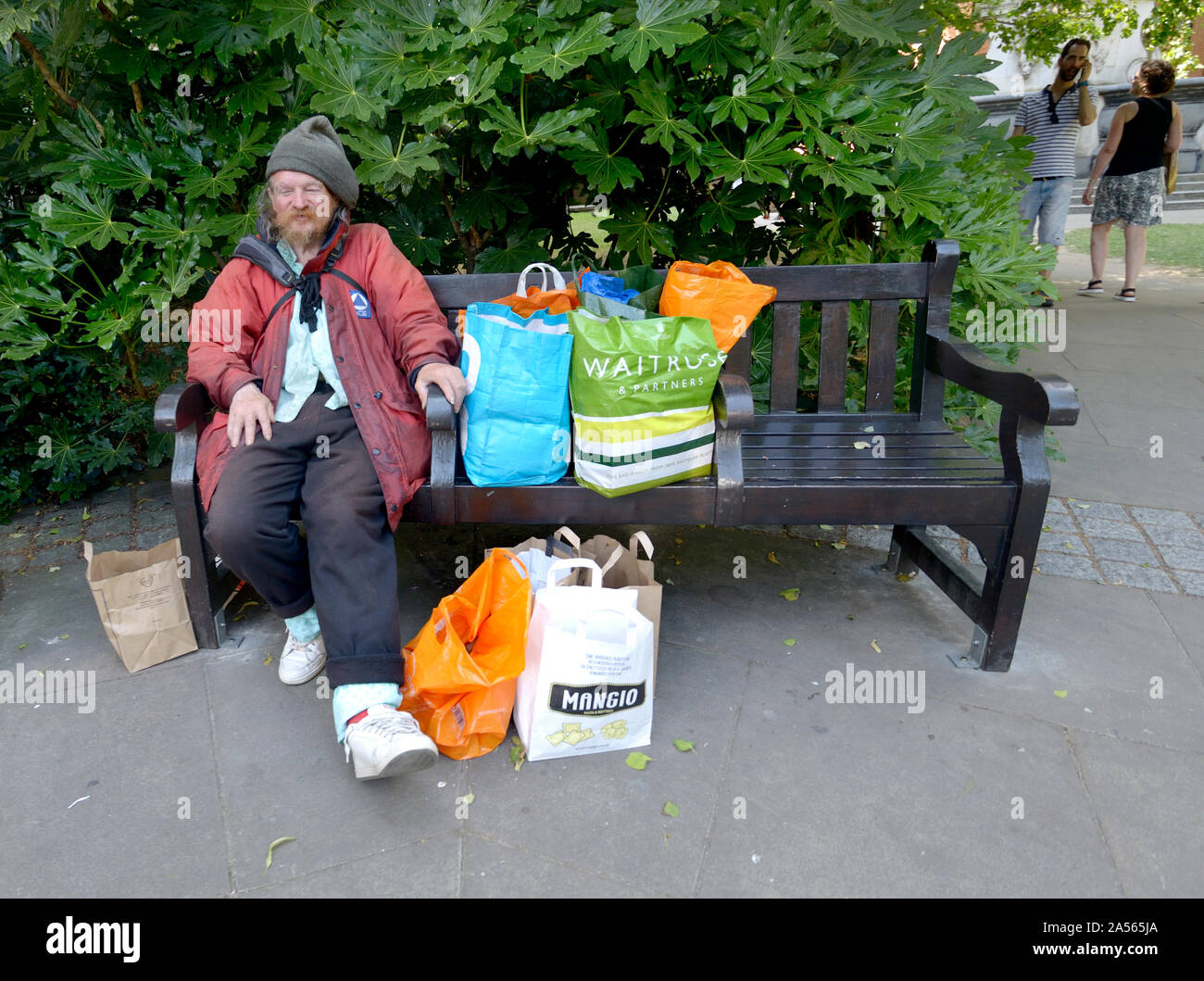 London, England, UK. Homeless man sitting on a bench in the grounds of ...