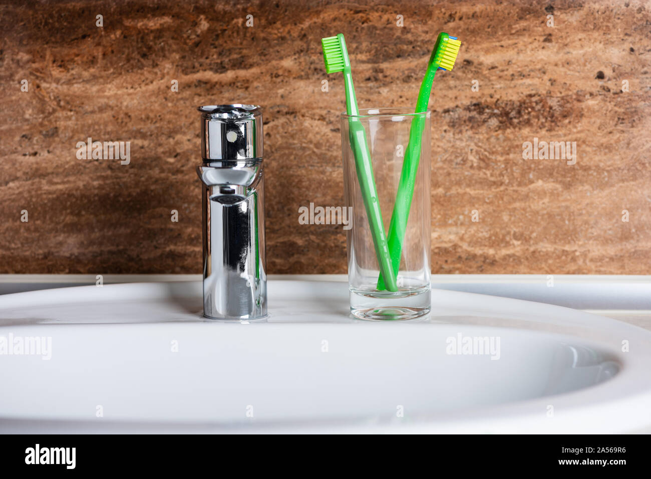 Original and orthodontic toothbrushes in glass against bathroom ...