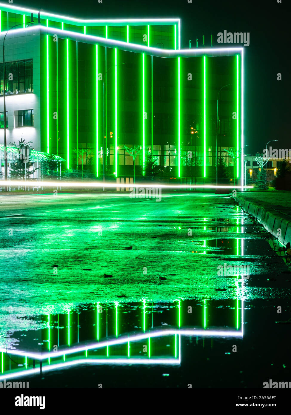 Modern tech building framed by a line of green neon lights. A ...