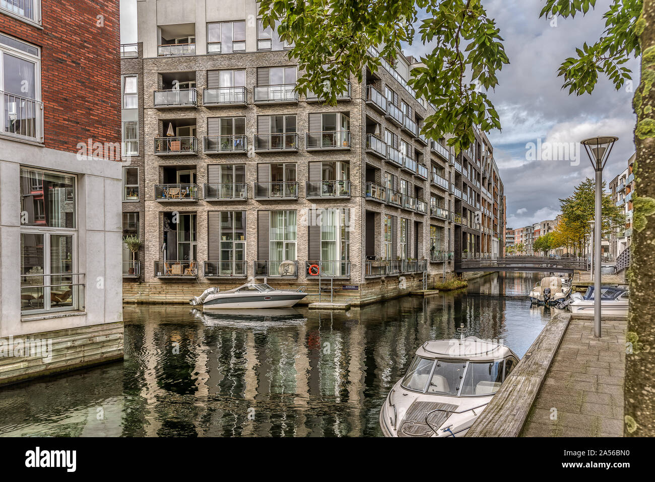 Waterfront apartments with boats at the quayside in the calm canal at ...