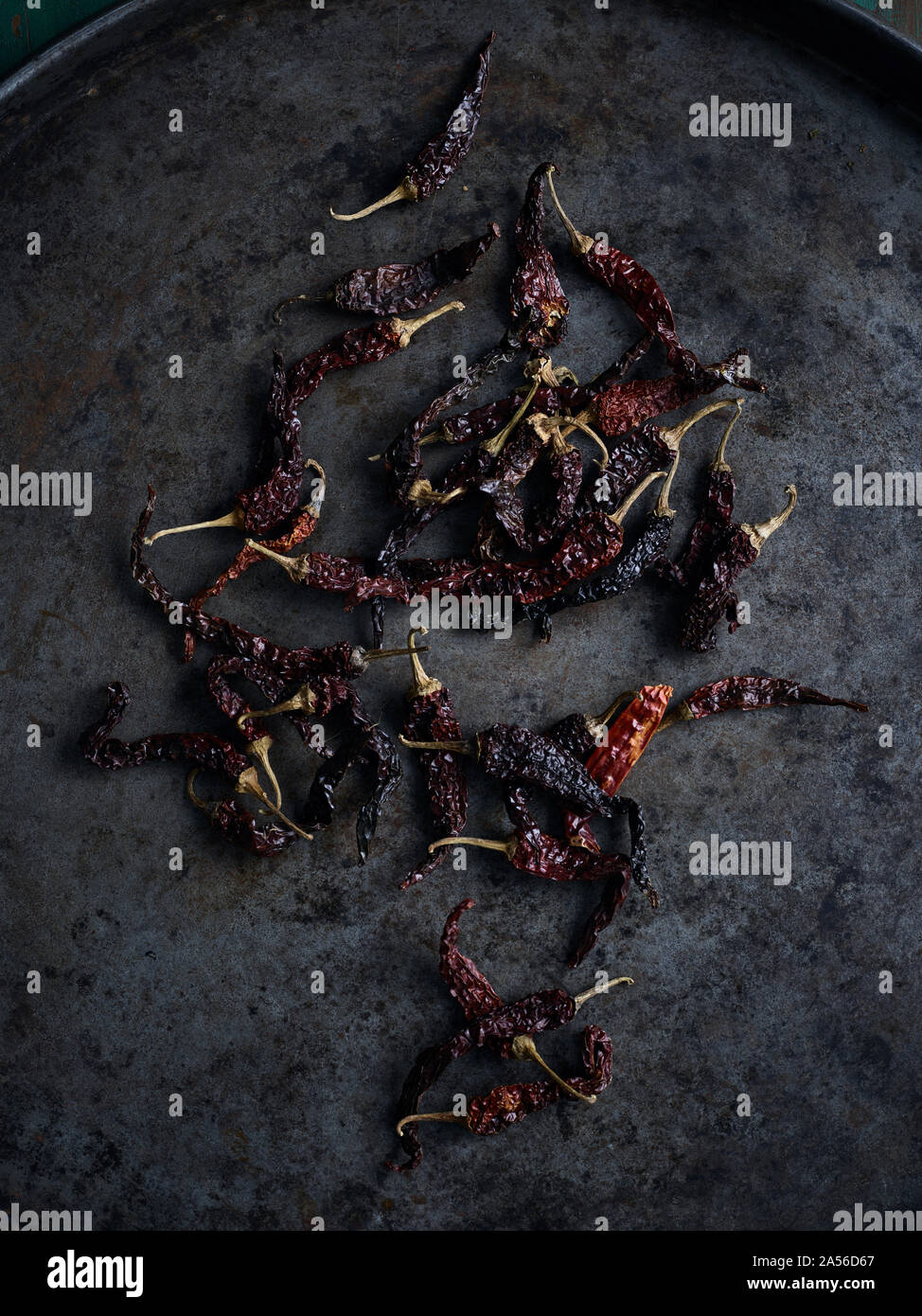 Rustic low key still life with scattered dried chillies, overhead view ...