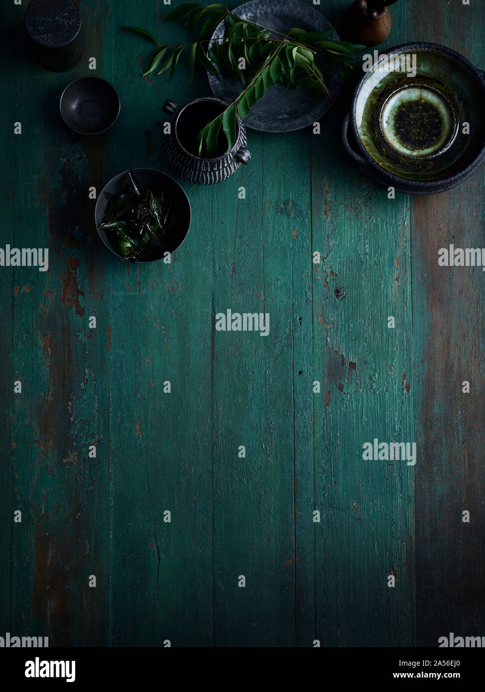 Rustic low key still life with bowls and cup on green wooden table ...