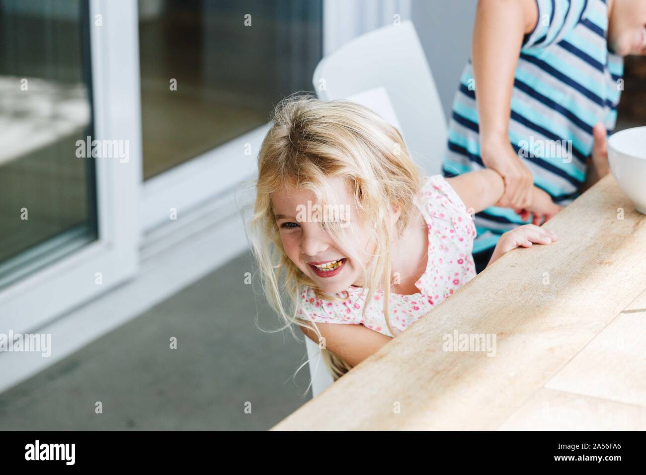 Boy pulling sister's hand playfully at dining table Stock Photo - Alamy