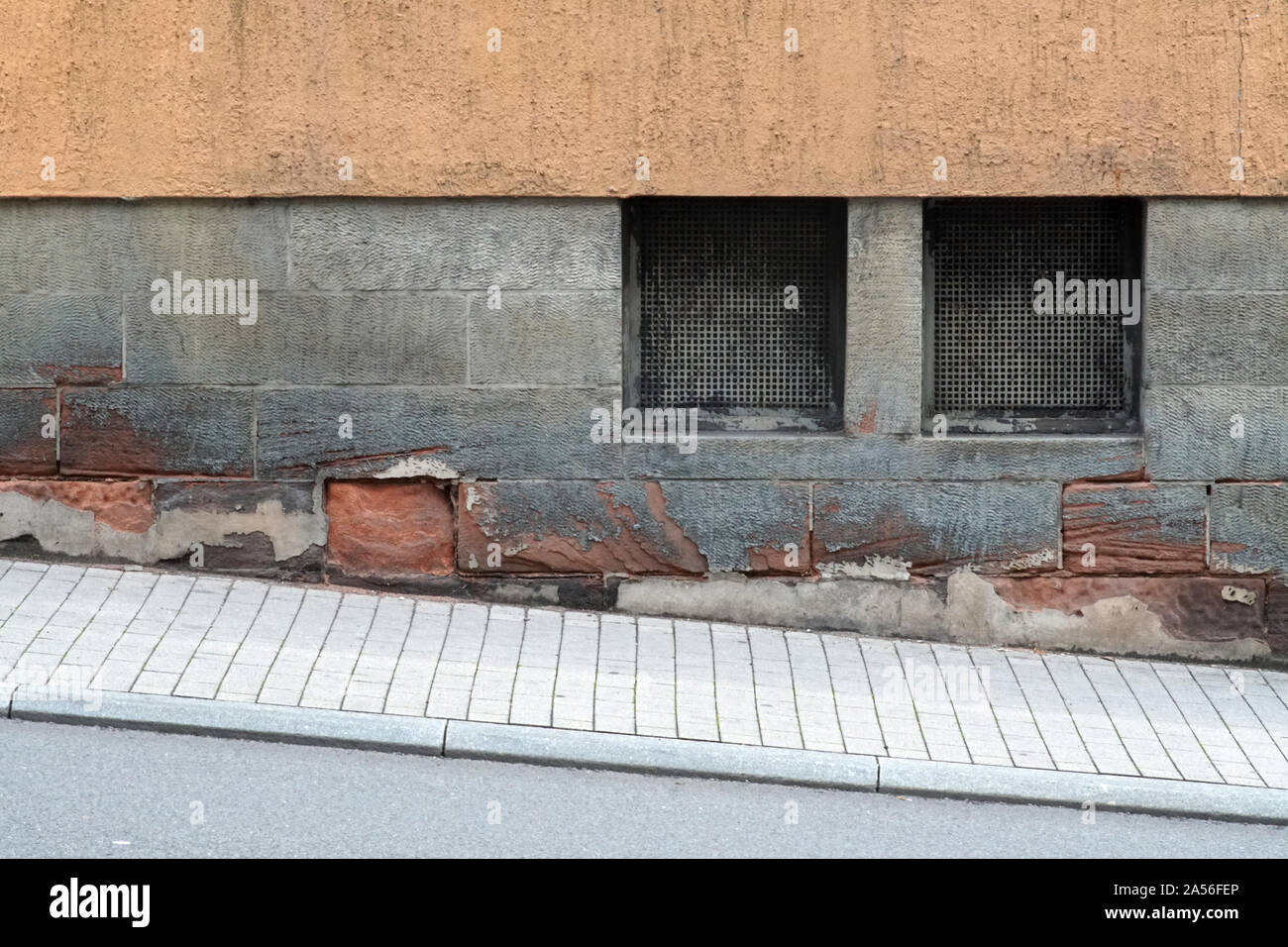 An old residential building with cellar windows on a walkway with slope ...