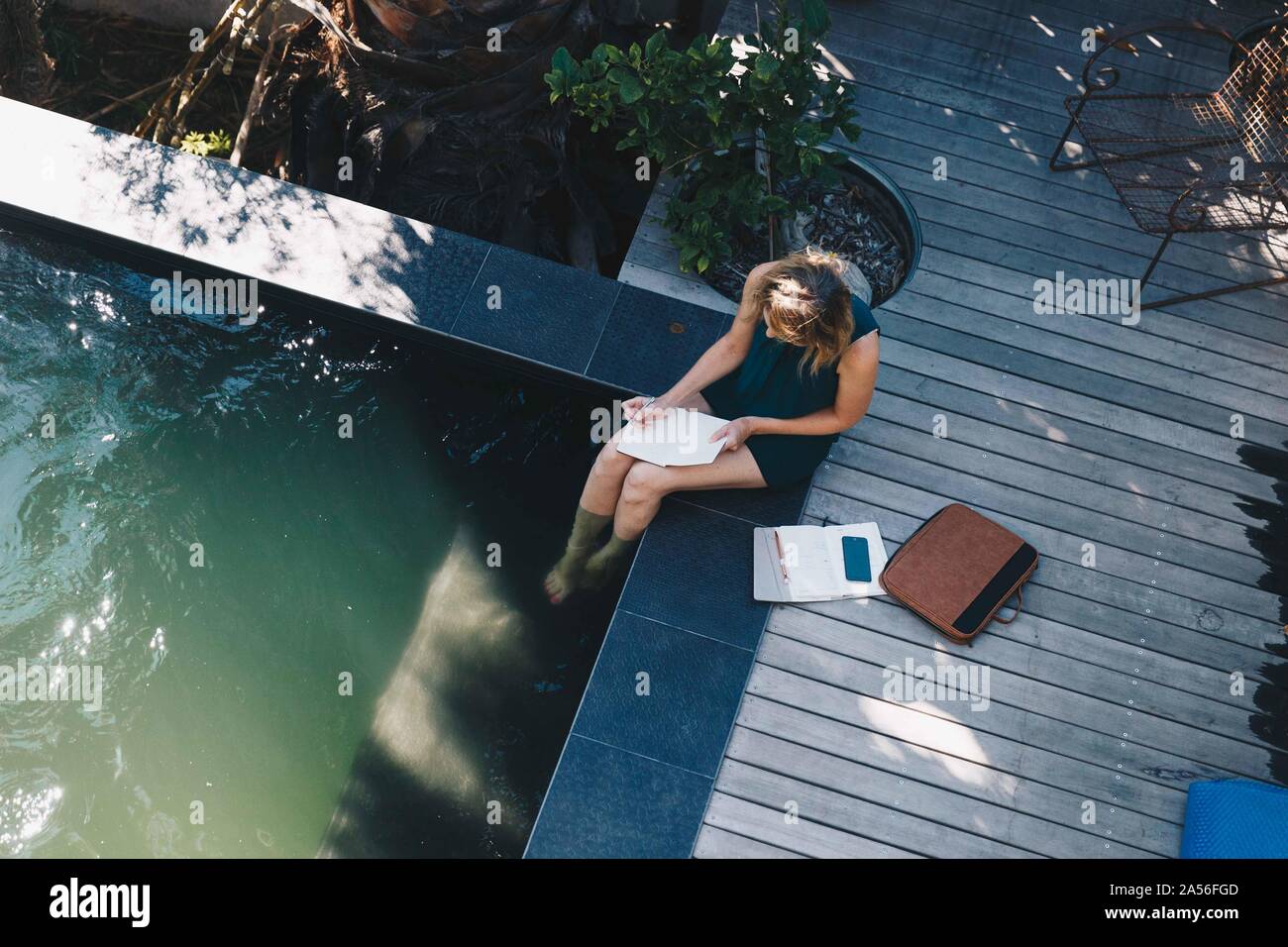 Businesswoman working on edge of swimming pool with legs in water Stock ...