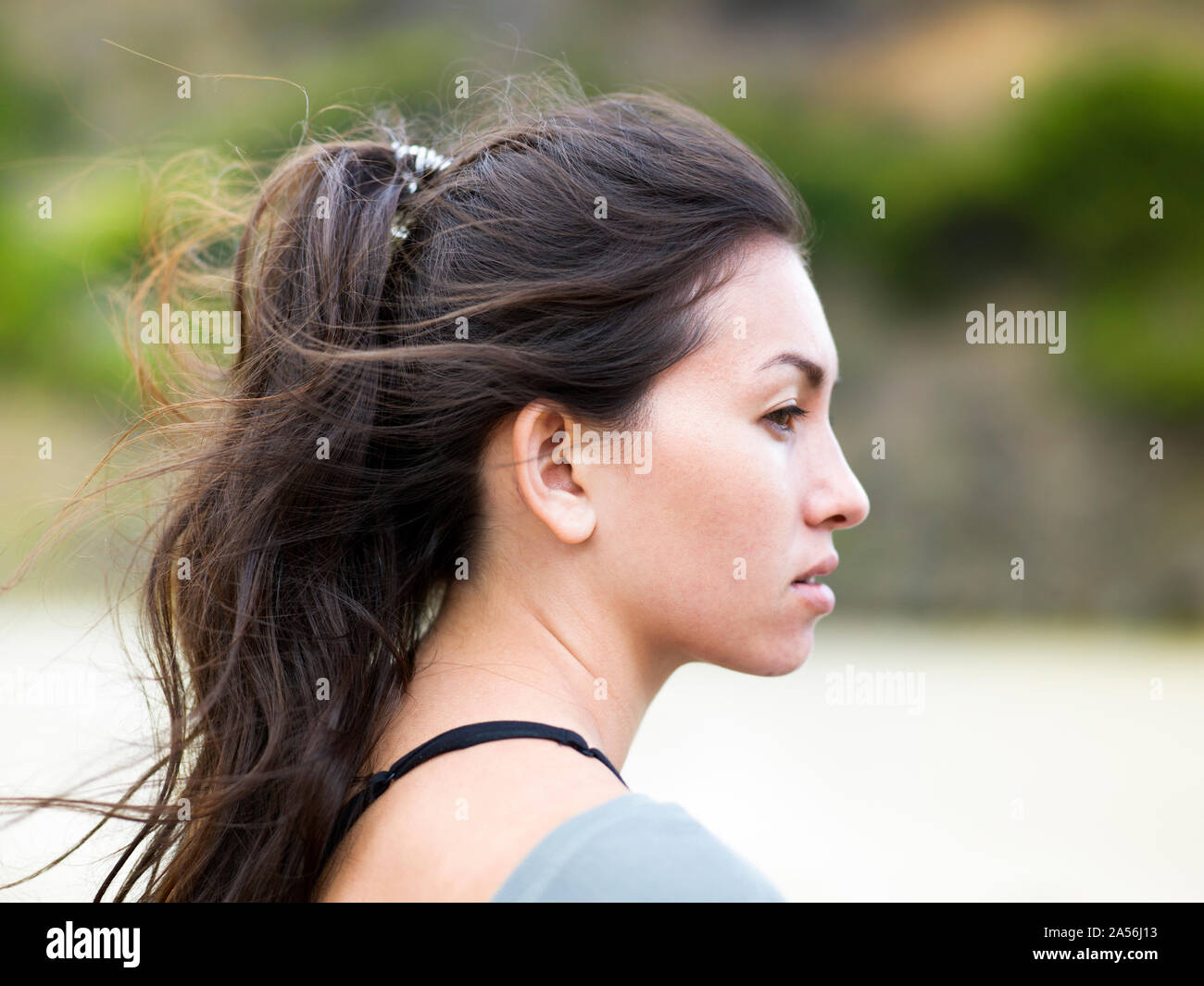 Young female surfer gazing from beach, head and shoulder side view ...