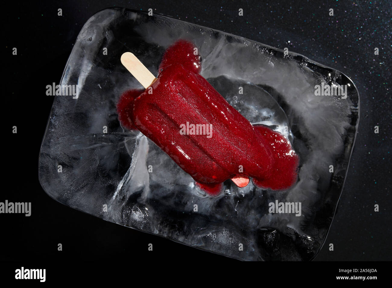 Homemade raspberry iced lolly melting on block of ice, overhead view ...