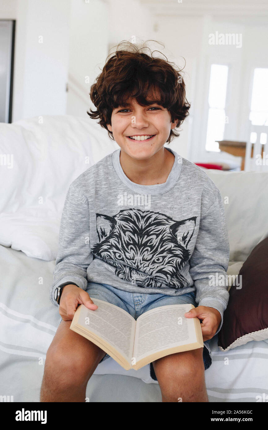 Boy reading book on sofa at home Stock Photo - Alamy