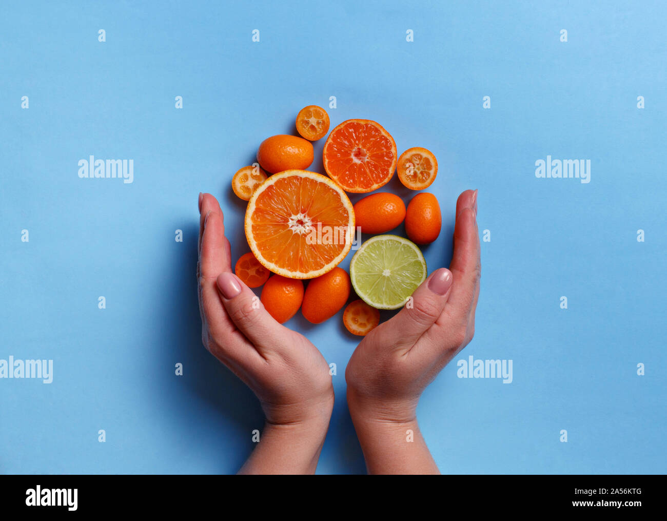 Citrus fruits with hands on a blue background Stock Photo - Alamy
