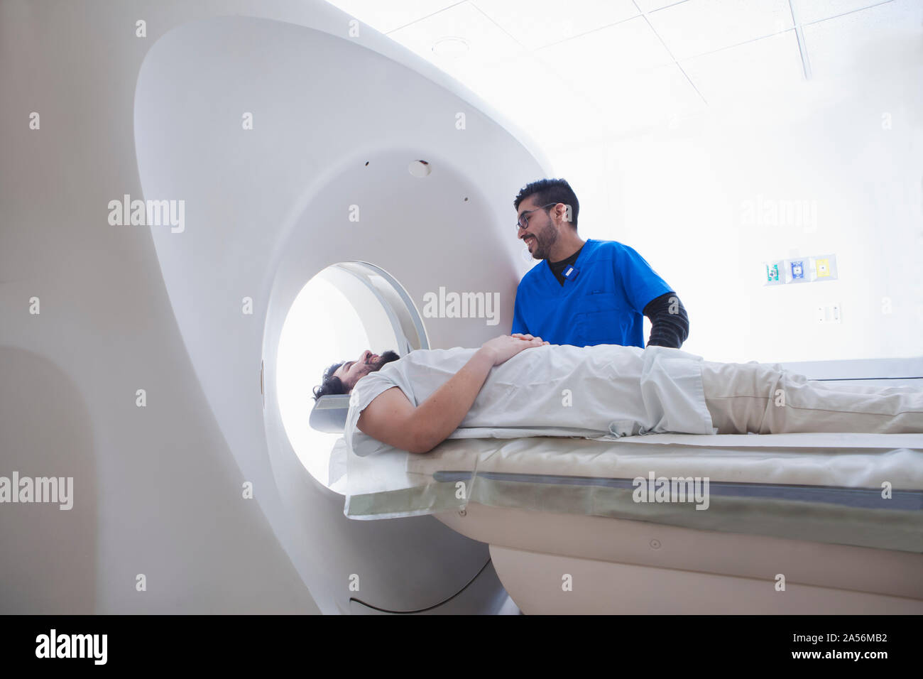 Young male radiographer operating CT scanner in radiology department ...