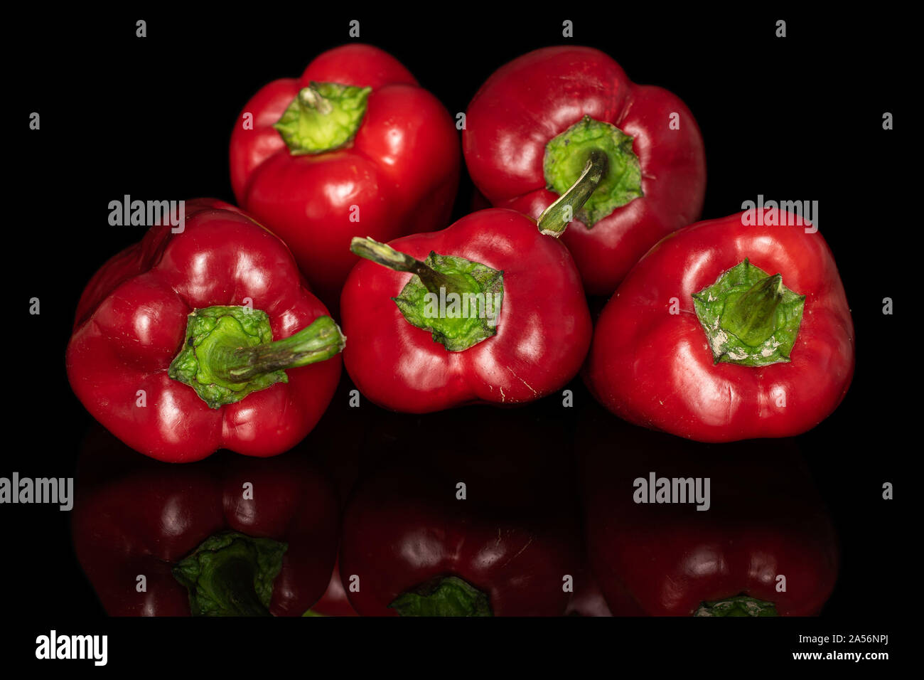 Group of five whole sweet red bell pepper isolated on black glass Stock ...