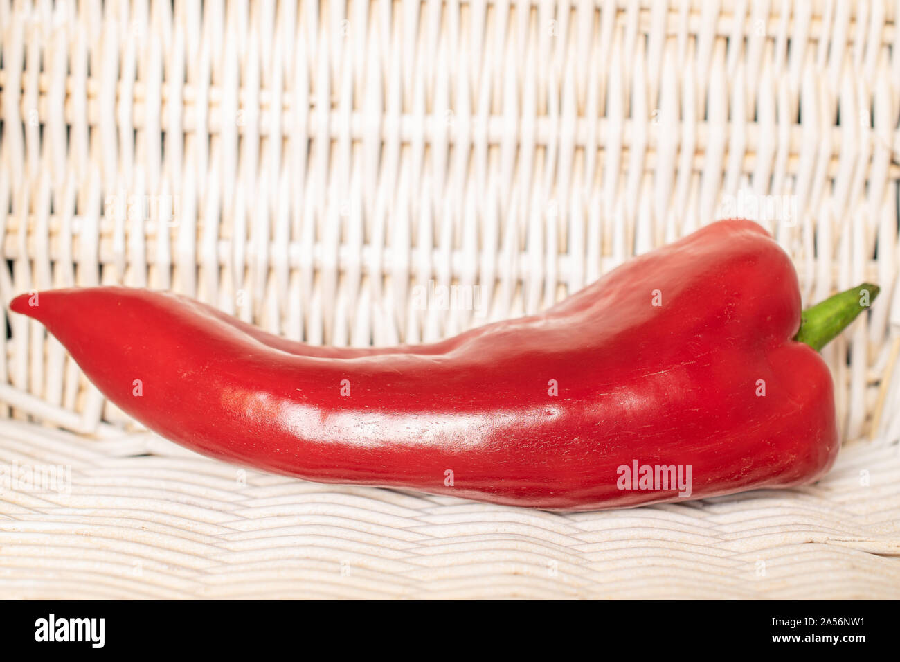 One whole sweet red bell pepper with braided rattan behind Stock Photo ...