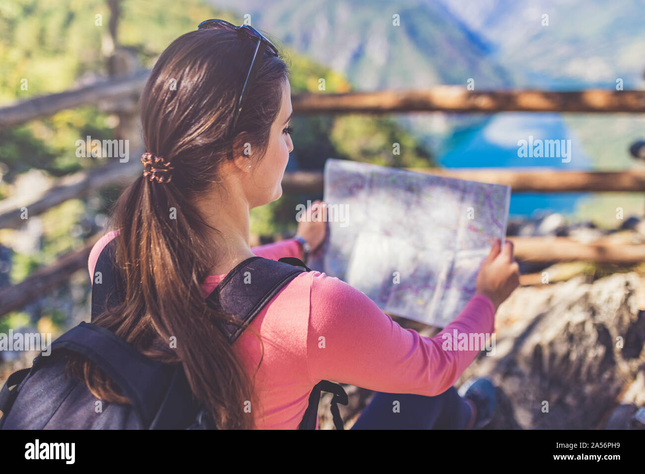 Young traveler holding map and looking at trekking plan on hill above ...