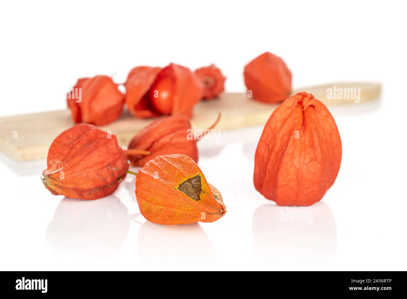 Group of eight whole fresh orange physalis on wooden cutting board ...