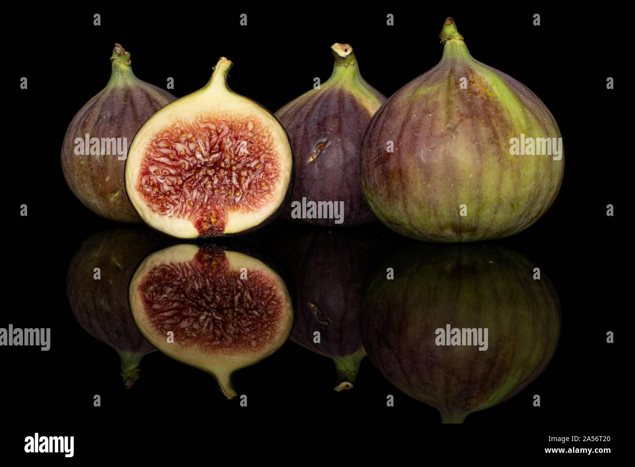 Group of three whole one half of sweet purple fig isolated on black ...