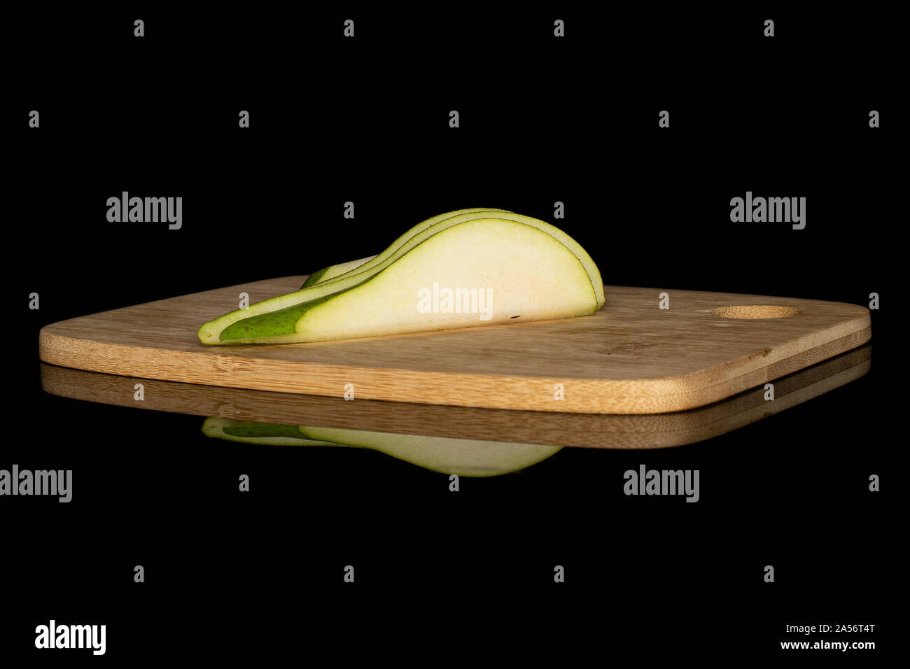 Group of three slices of fresh green pear on bamboo cutting board ...