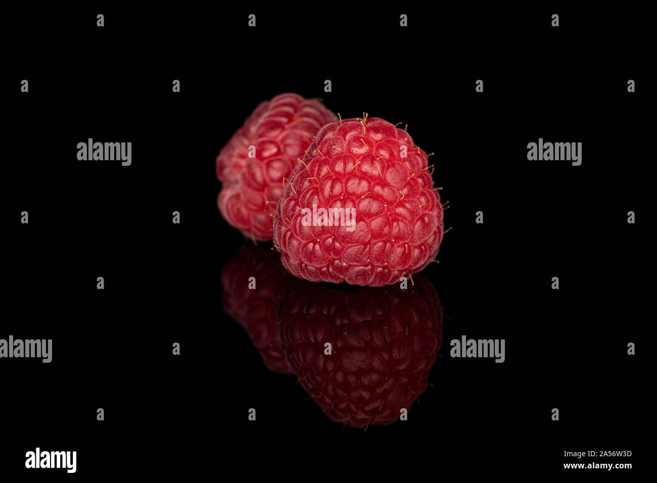 Group of two whole fresh red raspberry isolated on black glass Stock ...