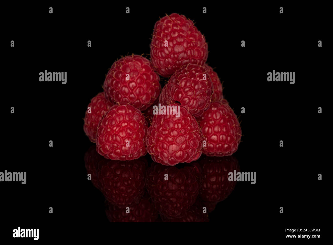 Group of seven whole fresh red raspberry isolated on black glass Stock ...