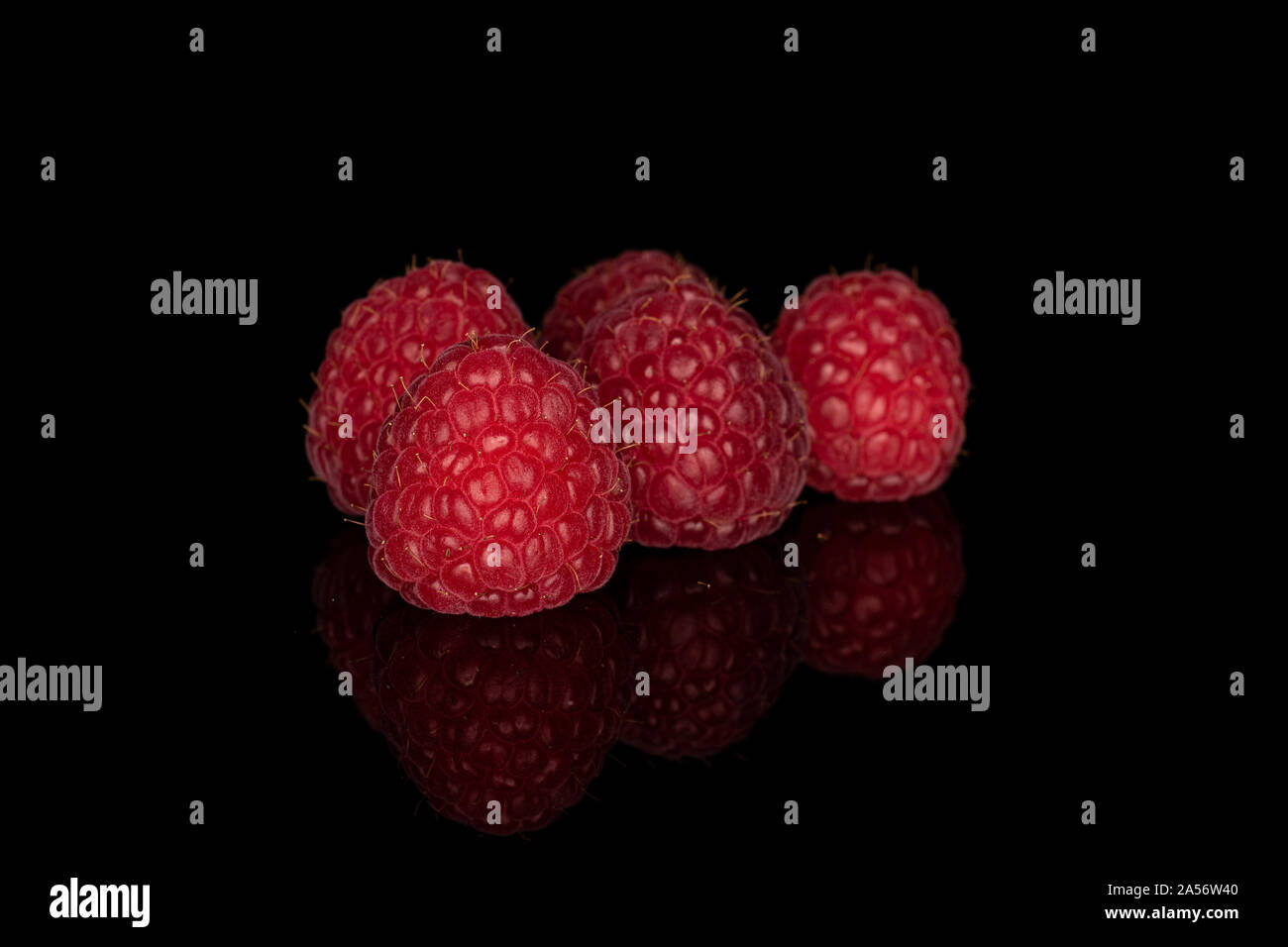 Group of five whole fresh red raspberry isolated on black glass Stock ...