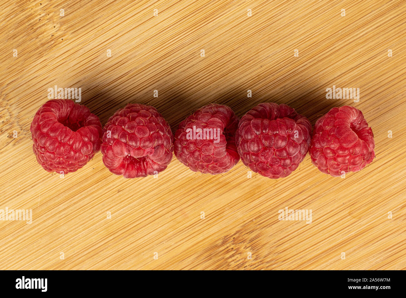 Group of five whole fresh red raspberry flatlay on light wood Stock ...