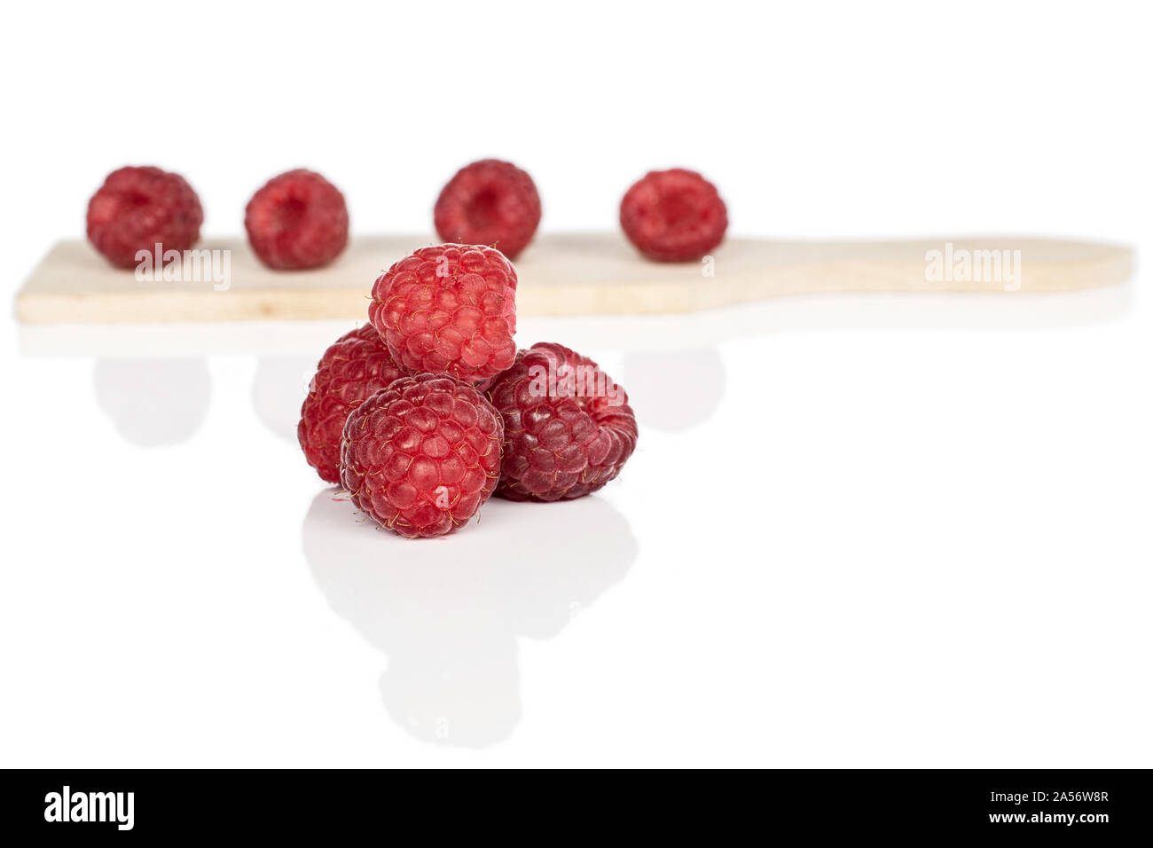 Group of seven whole fresh red raspberry on wooden cutting board ...