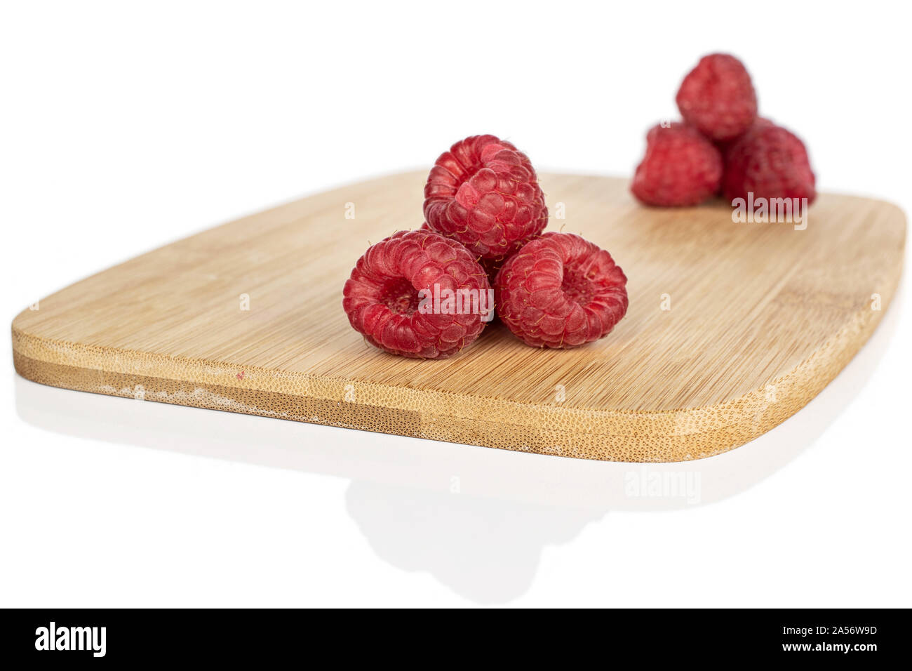 Group of six whole fresh red raspberry on bamboo cutting board isolated ...