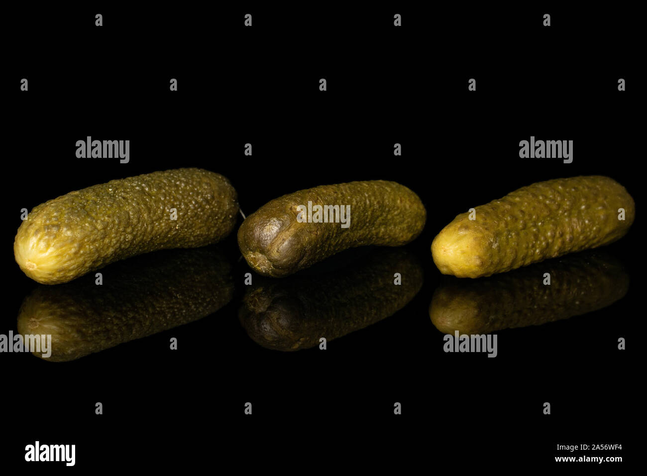 Group of three whole sour green pickle isolated on black glass Stock ...