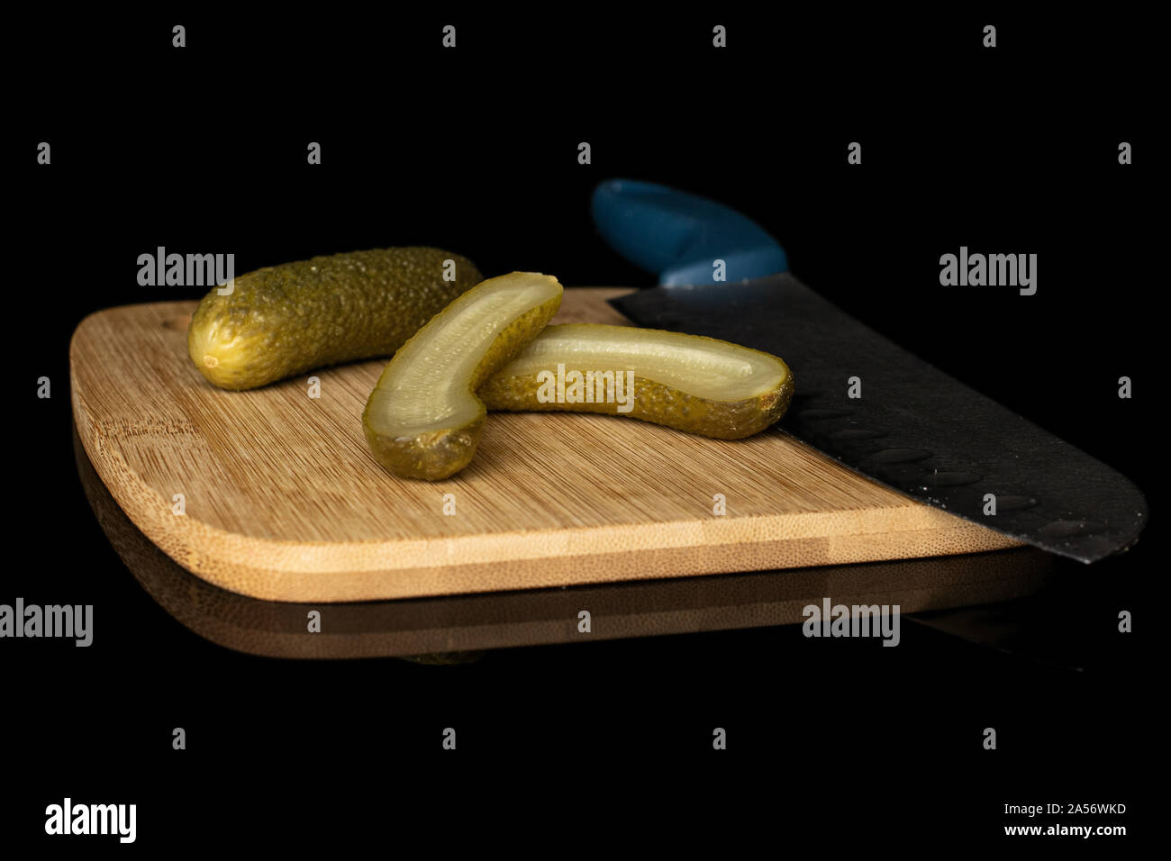 Group of one whole two halves of sour green pickle on bamboo cutting ...