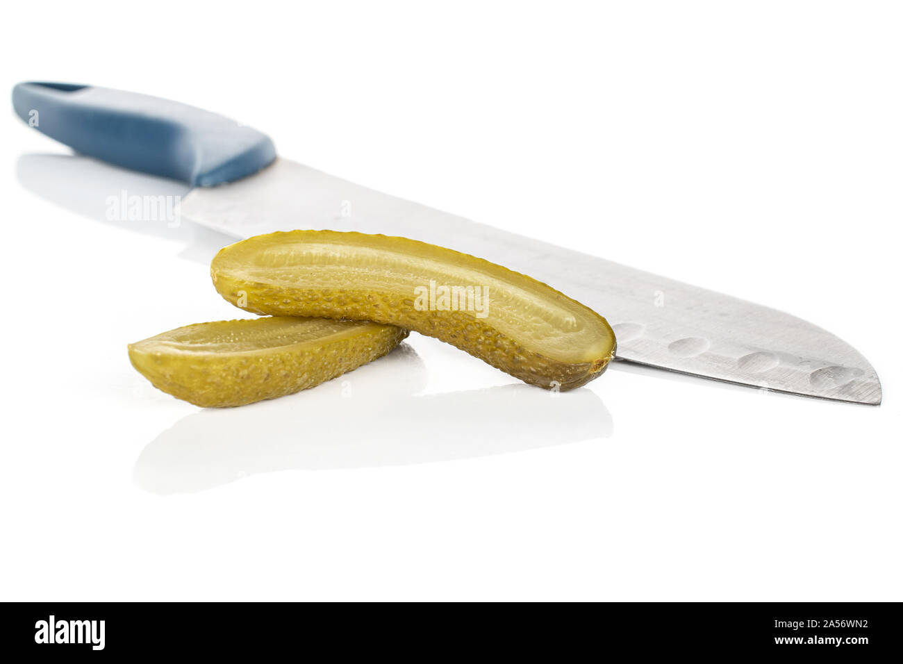 Group of two halves of sour green pickle crossed with steel knife ...
