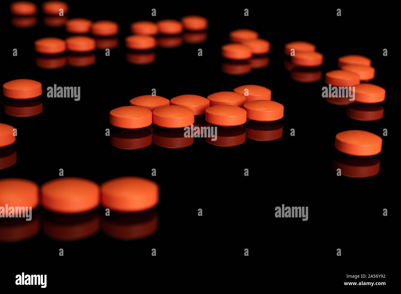 Lot of whole bright orange tablet pharmacy isolated on black glass ...