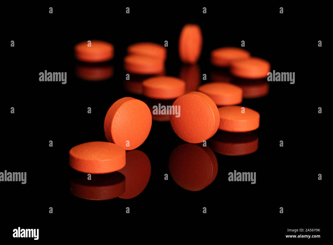 Group of twelve whole orange tablet pharmacy isolated on black glass ...
